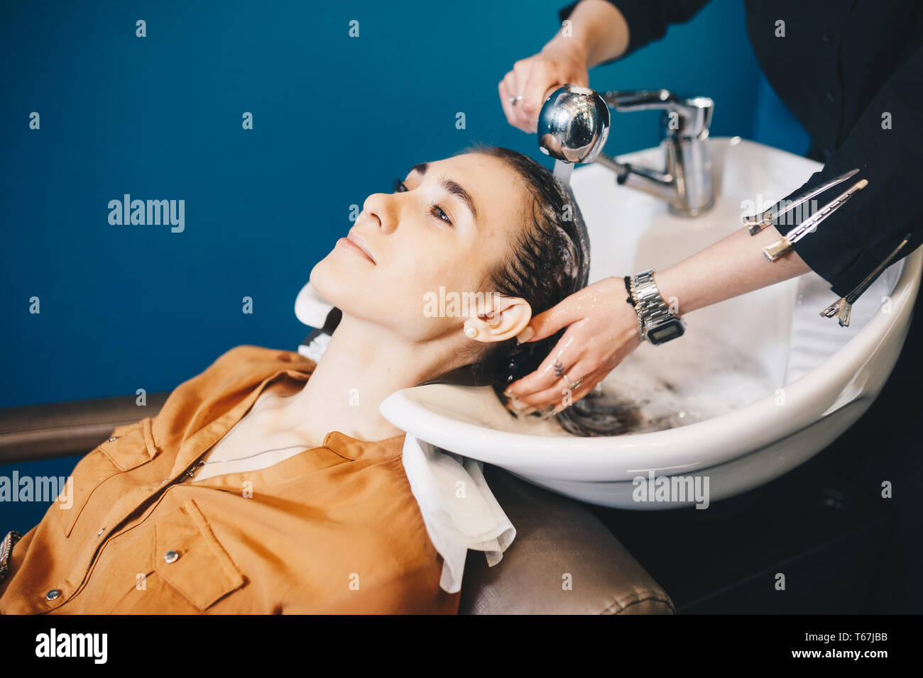 beauty and people concept. Hairdresser washing hair of happy young ...
