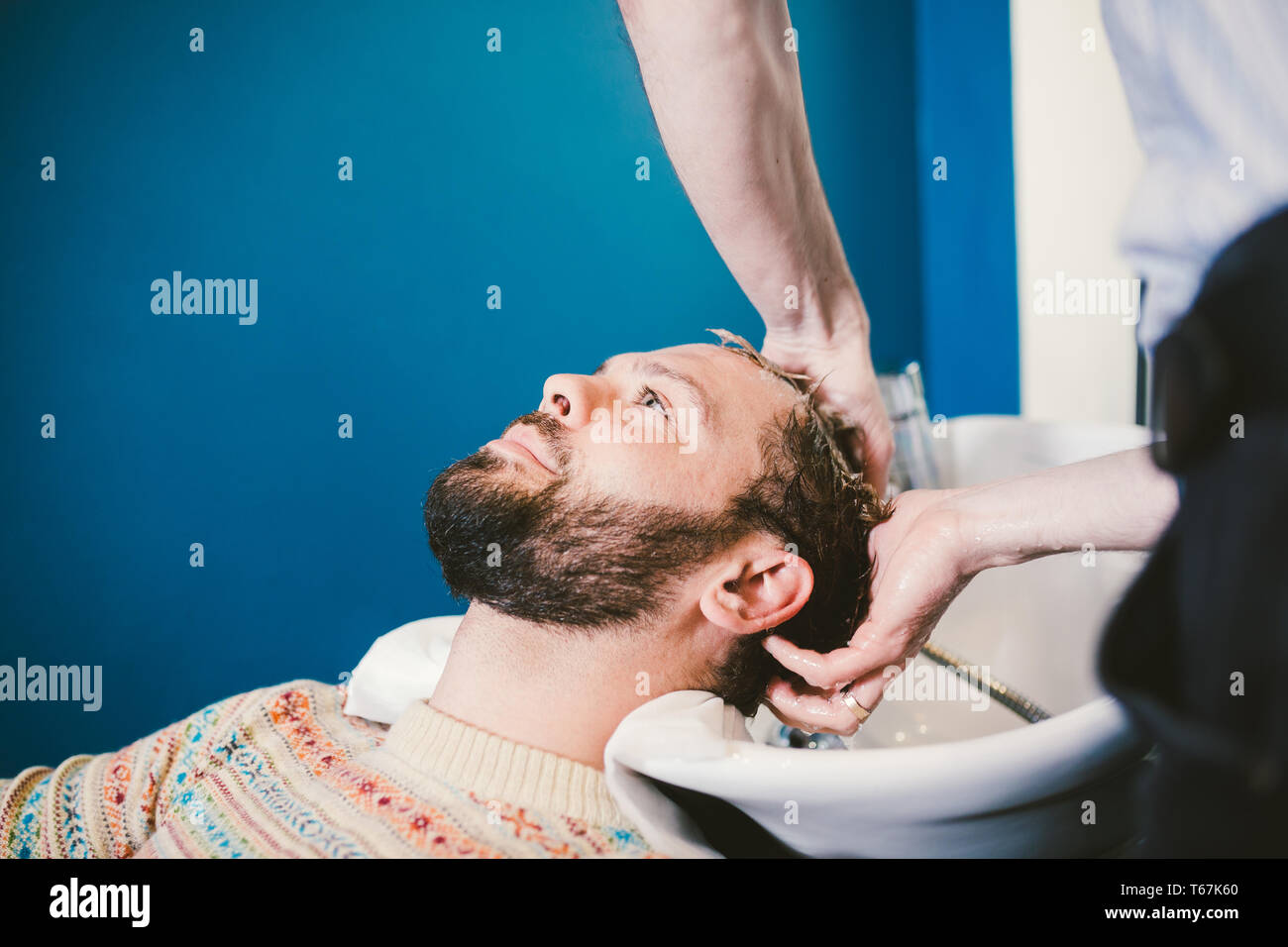 Barbershop theme. Barber is washing the head of the bearded man in the ...