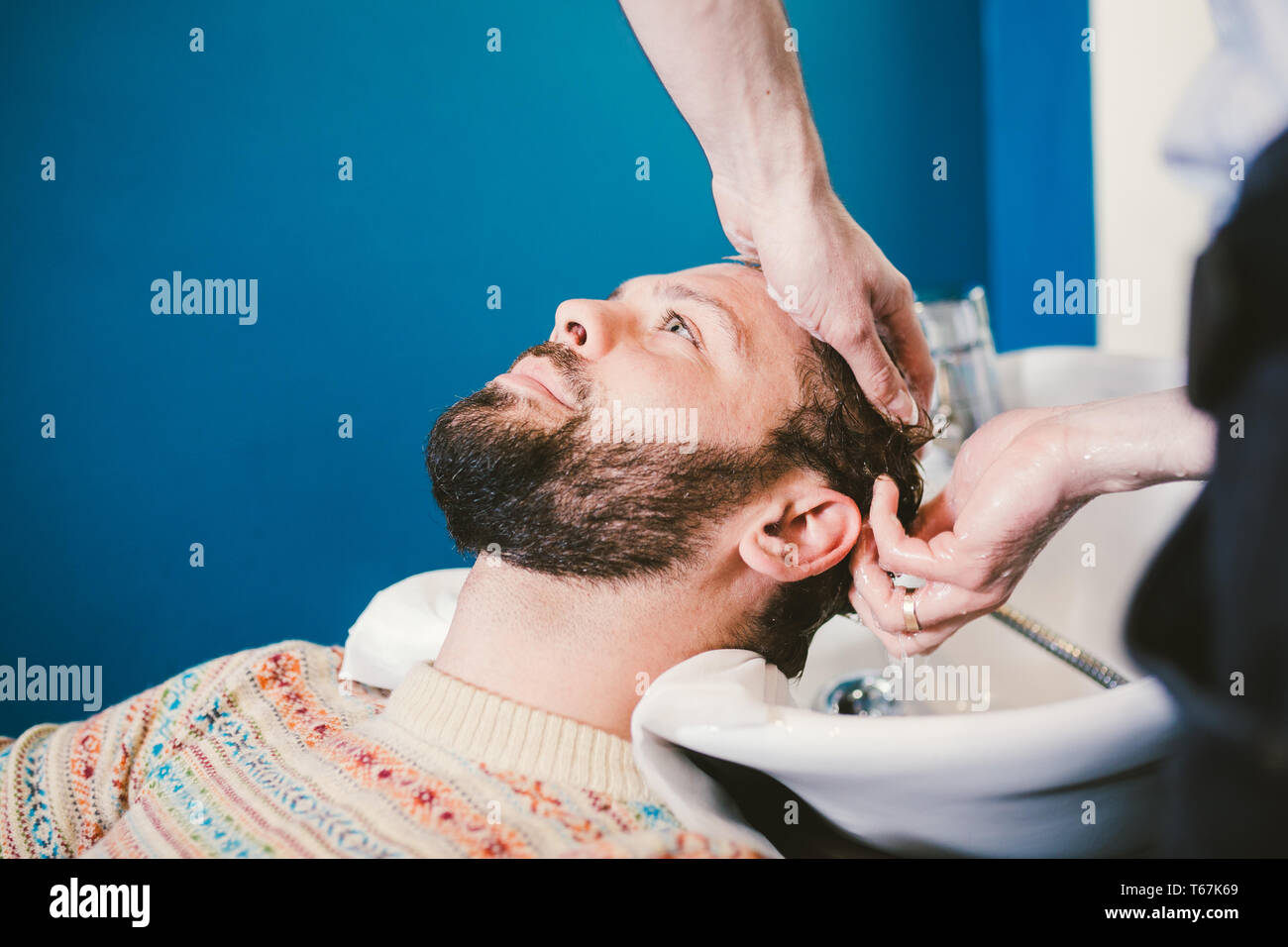 Barbershop theme. Barber is washing the head of the bearded man in the ...