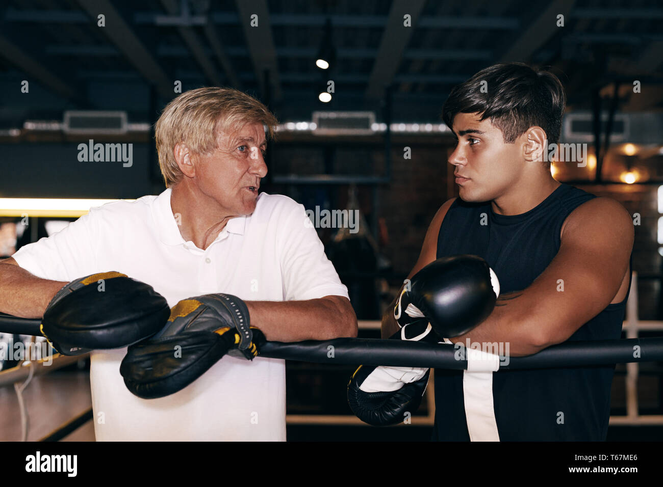 Young boxer listening to his mature trainer. Side view of a two sport ...