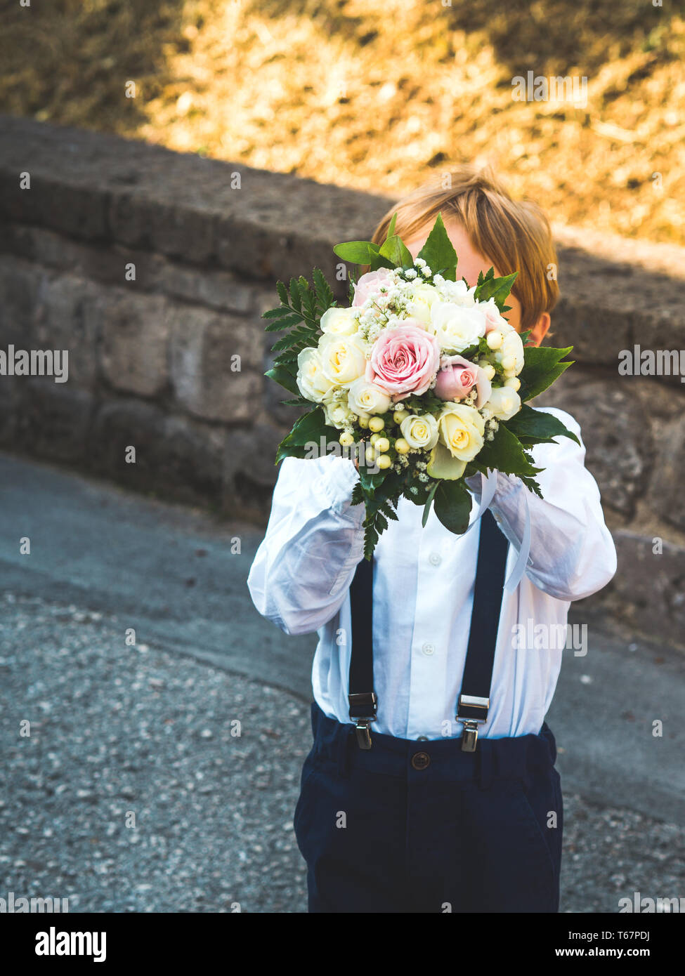 Little cute ring bearer at garden wedding playing with flower bouquet ...