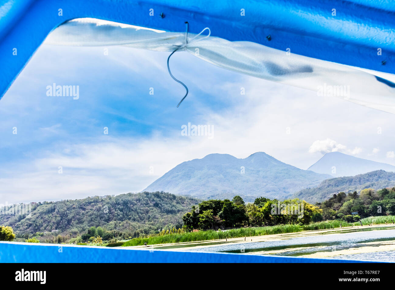 Open boat window frames view of shore on Lake Atitlan in Guatemala ...