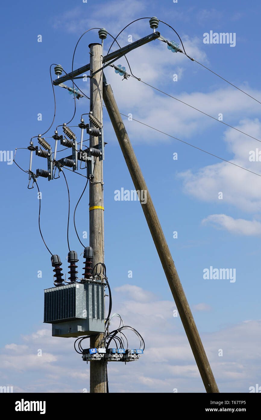 wooden power line pole with electric transformer in rural area, blue ...
