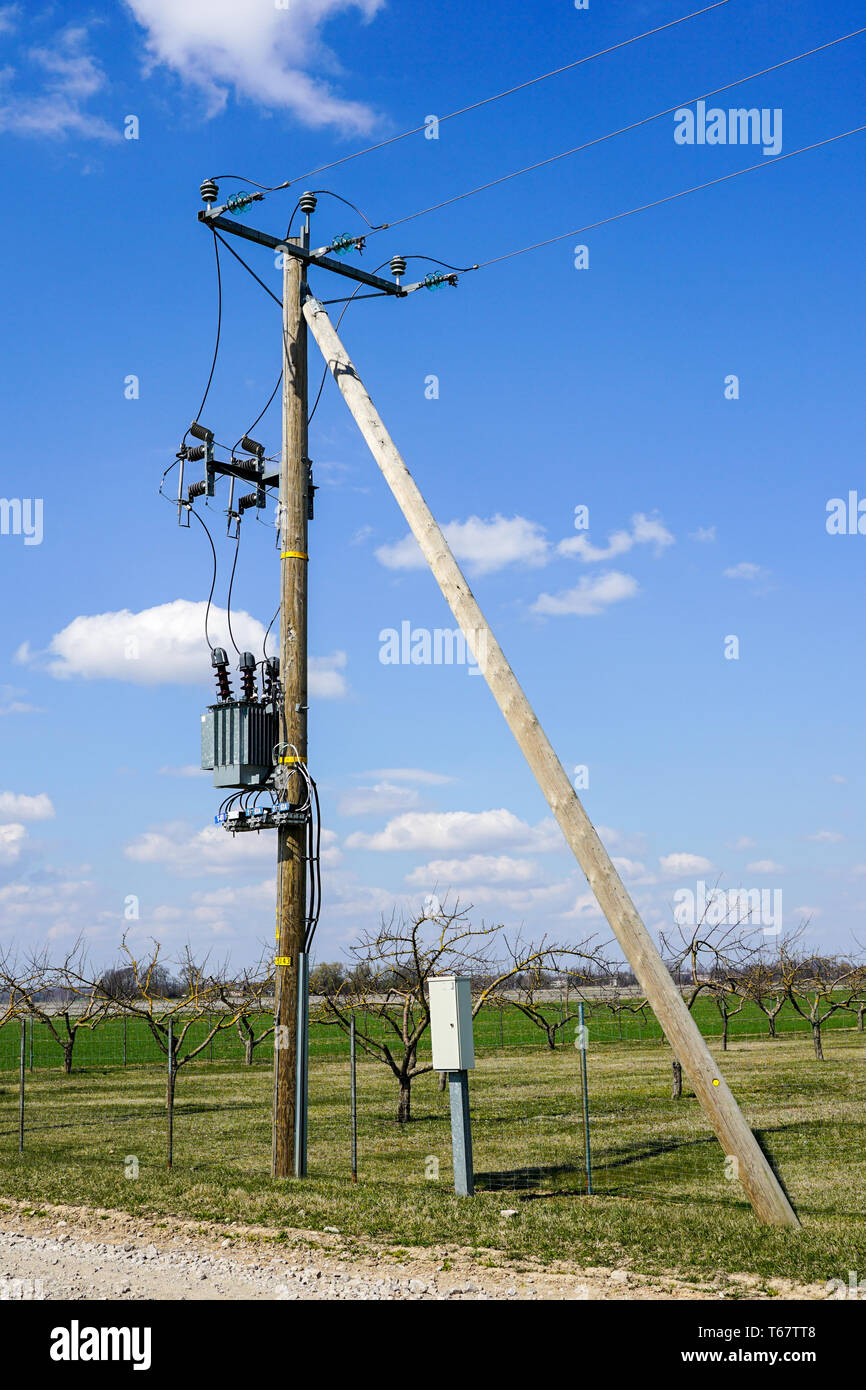 wooden power line pole with electric transformer in rural area, blue ...