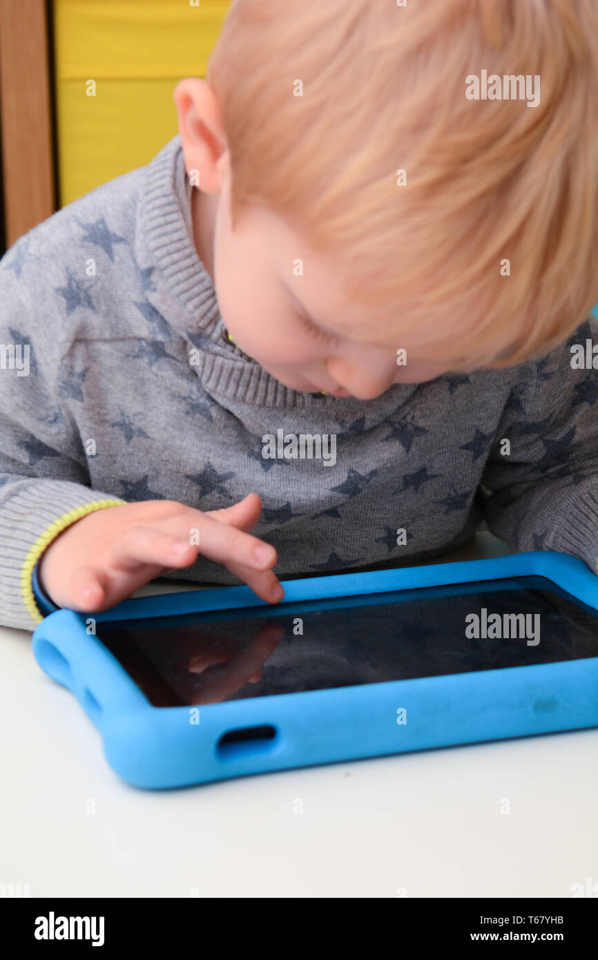 Happy young child is using a tablet computer. Boy is playing with ...