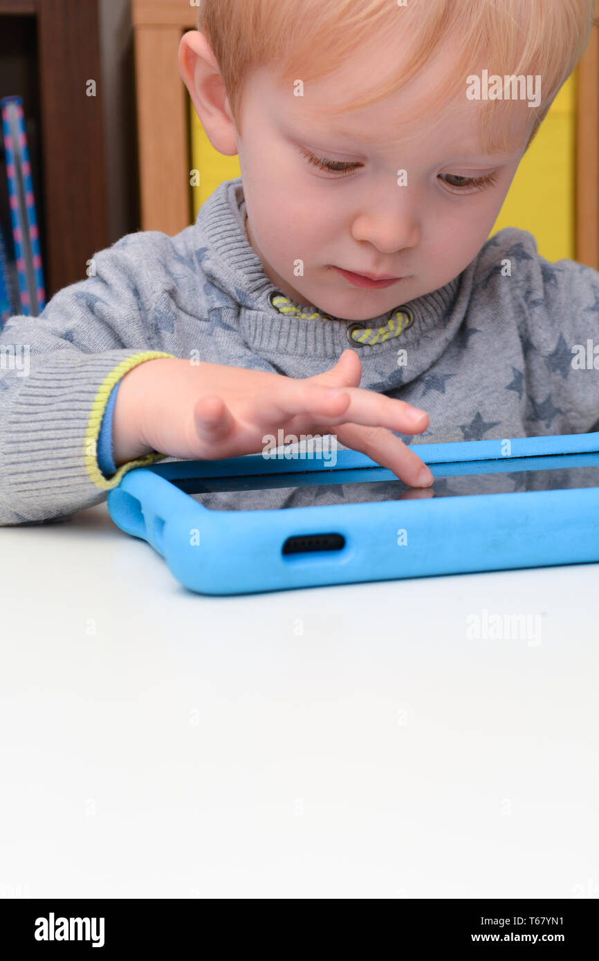 Happy young child is using a tablet computer. Boy is playing with ...