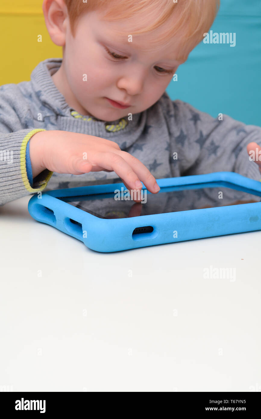 Happy young child is using a tablet computer. Boy is playing with ...
