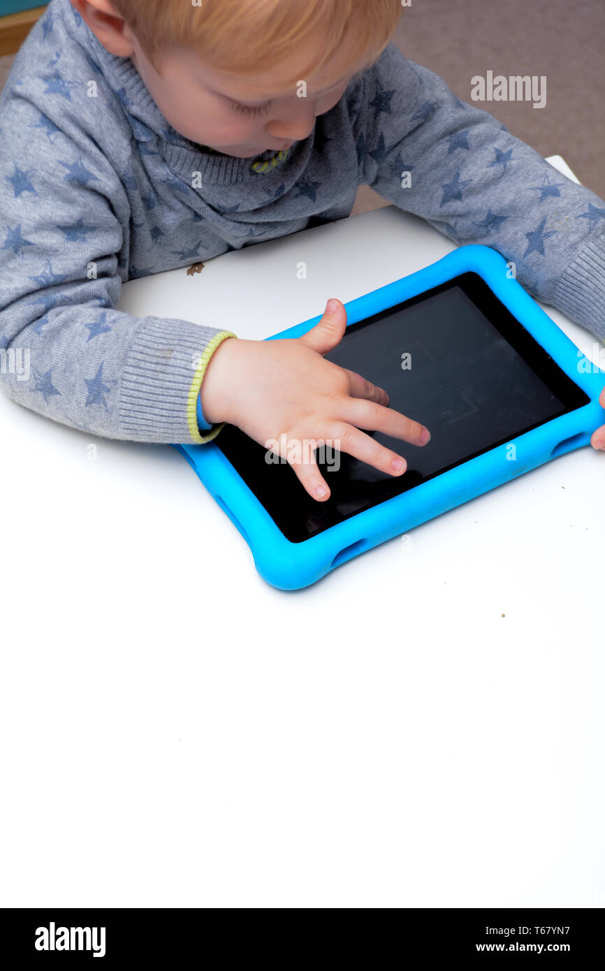 Happy young child is using a tablet computer. Boy is playing with ...