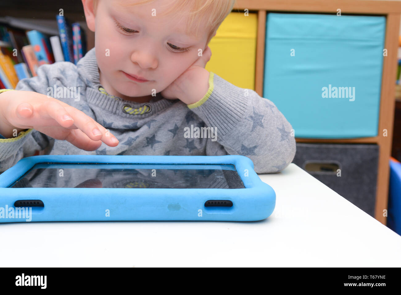Happy young child is using a tablet computer. Boy is playing with ...
