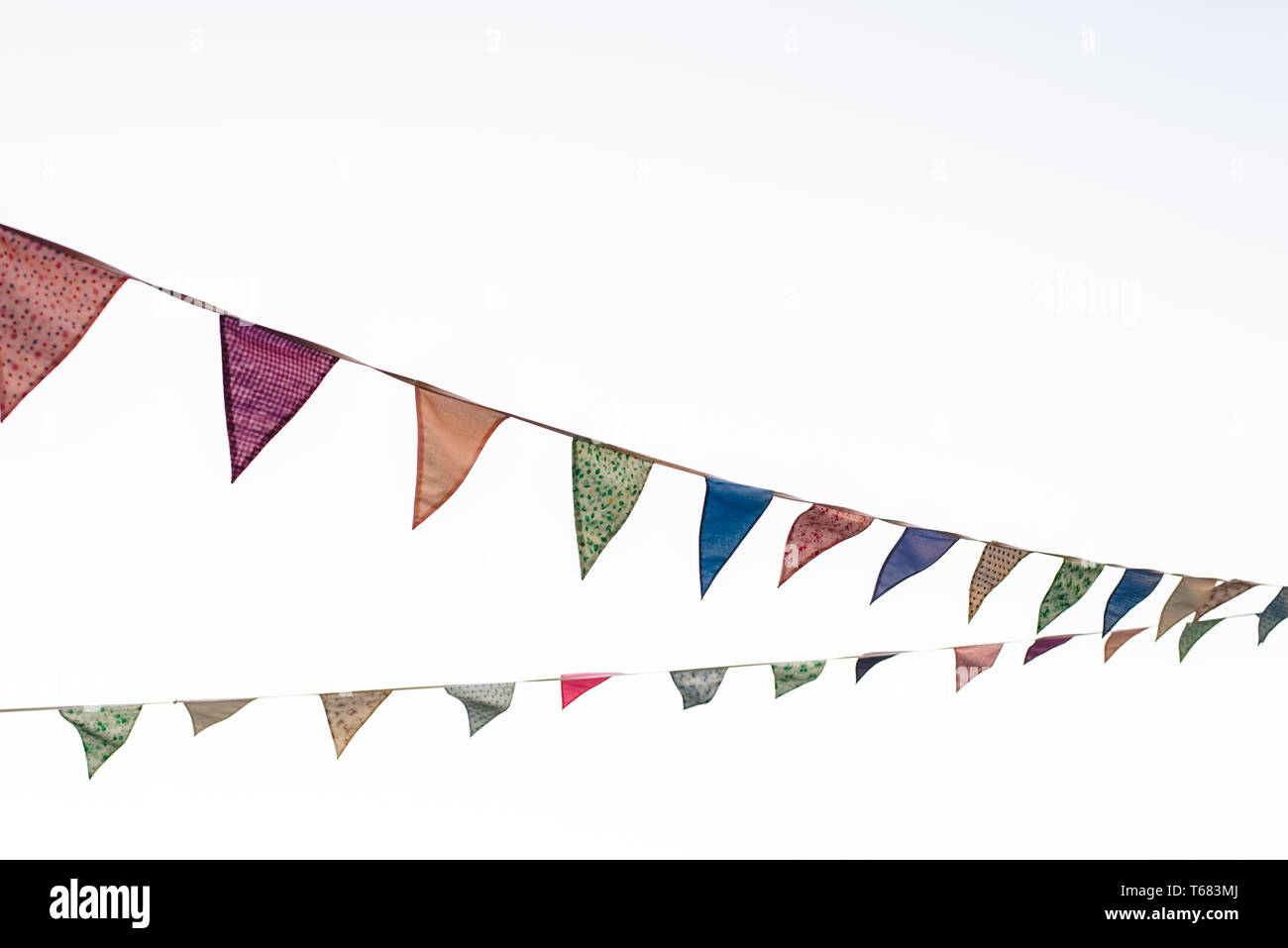Pennants with blue sky background and pale colors hanging on a rope ...
