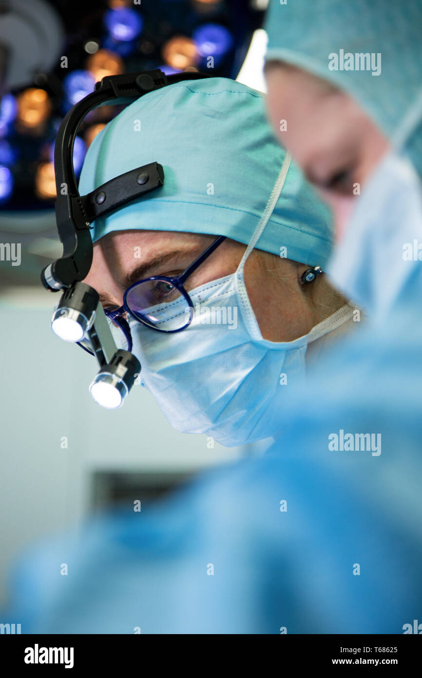 Surgeon and his assistant performing cosmetic surgery on nose in ...