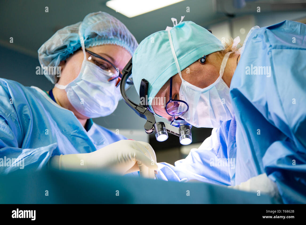 Surgeon and his assistant performing cosmetic surgery on nose in ...