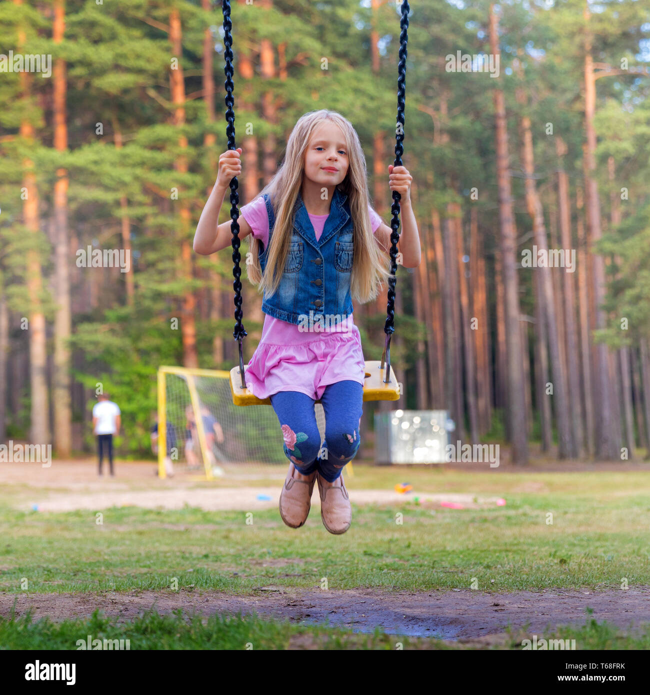 Pretty little blonde girl swinging outdoors on playground Stock Photo ...