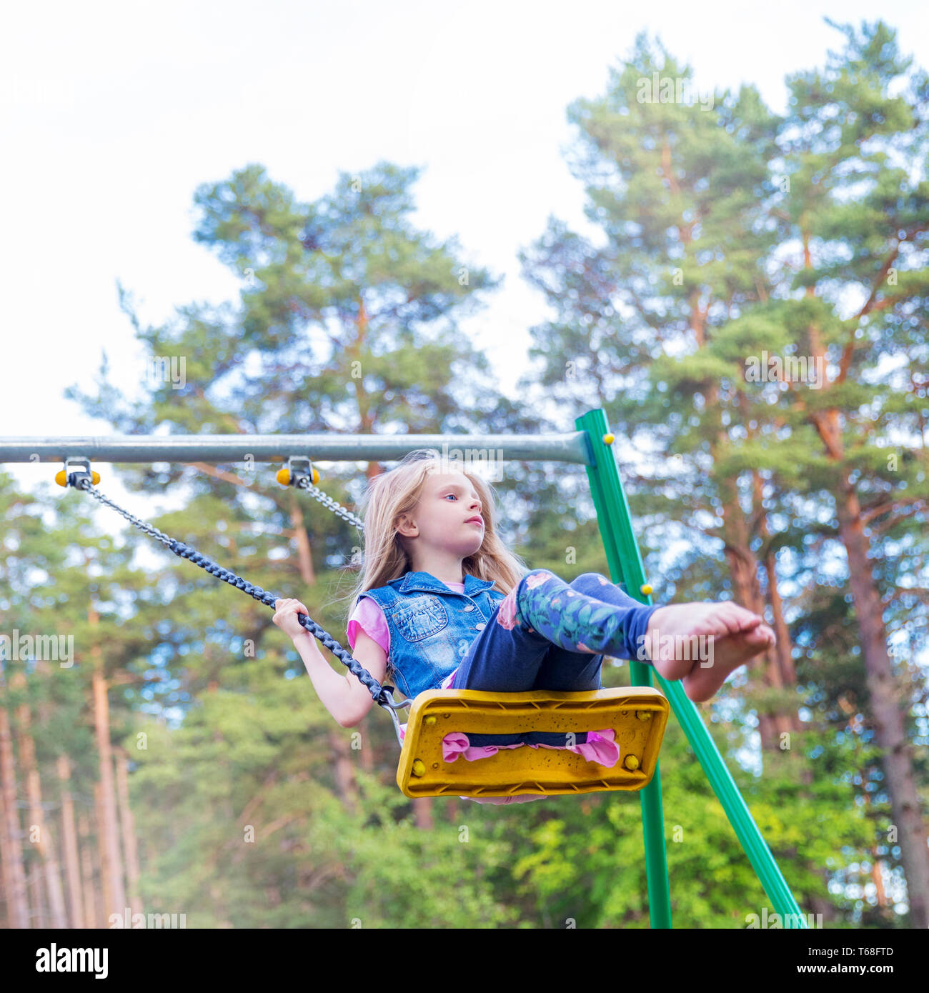 Pretty little blonde girl swinging outdoors on playground Stock Photo ...