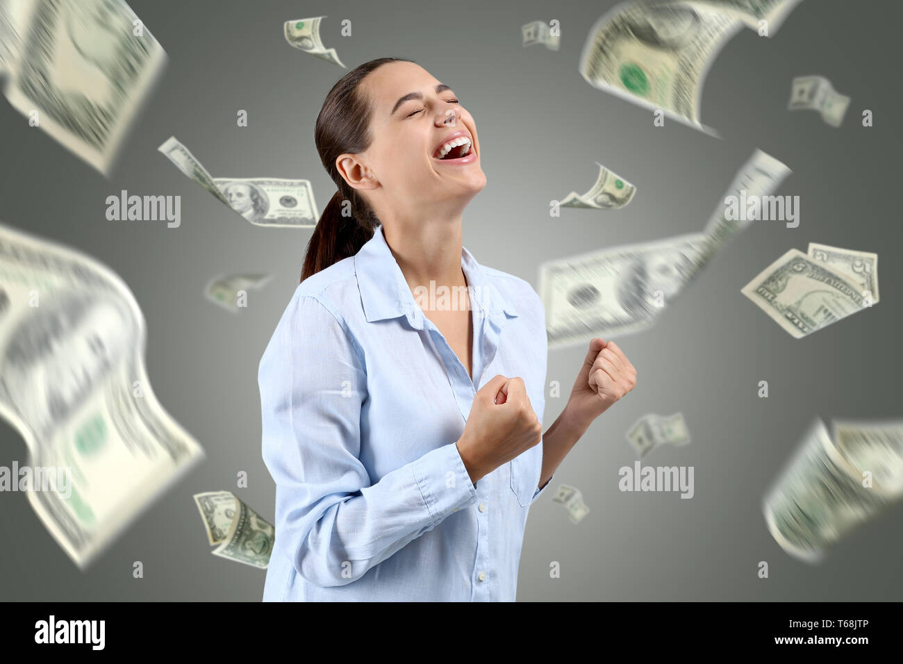 Happy rich woman with falling dollar banknotes on grey background Stock ...