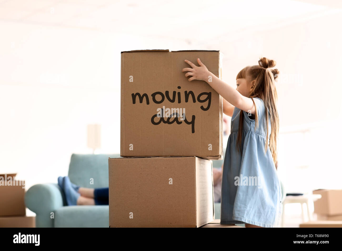 Cute girl stacking cardboard boxes in new flat on moving day Stock ...