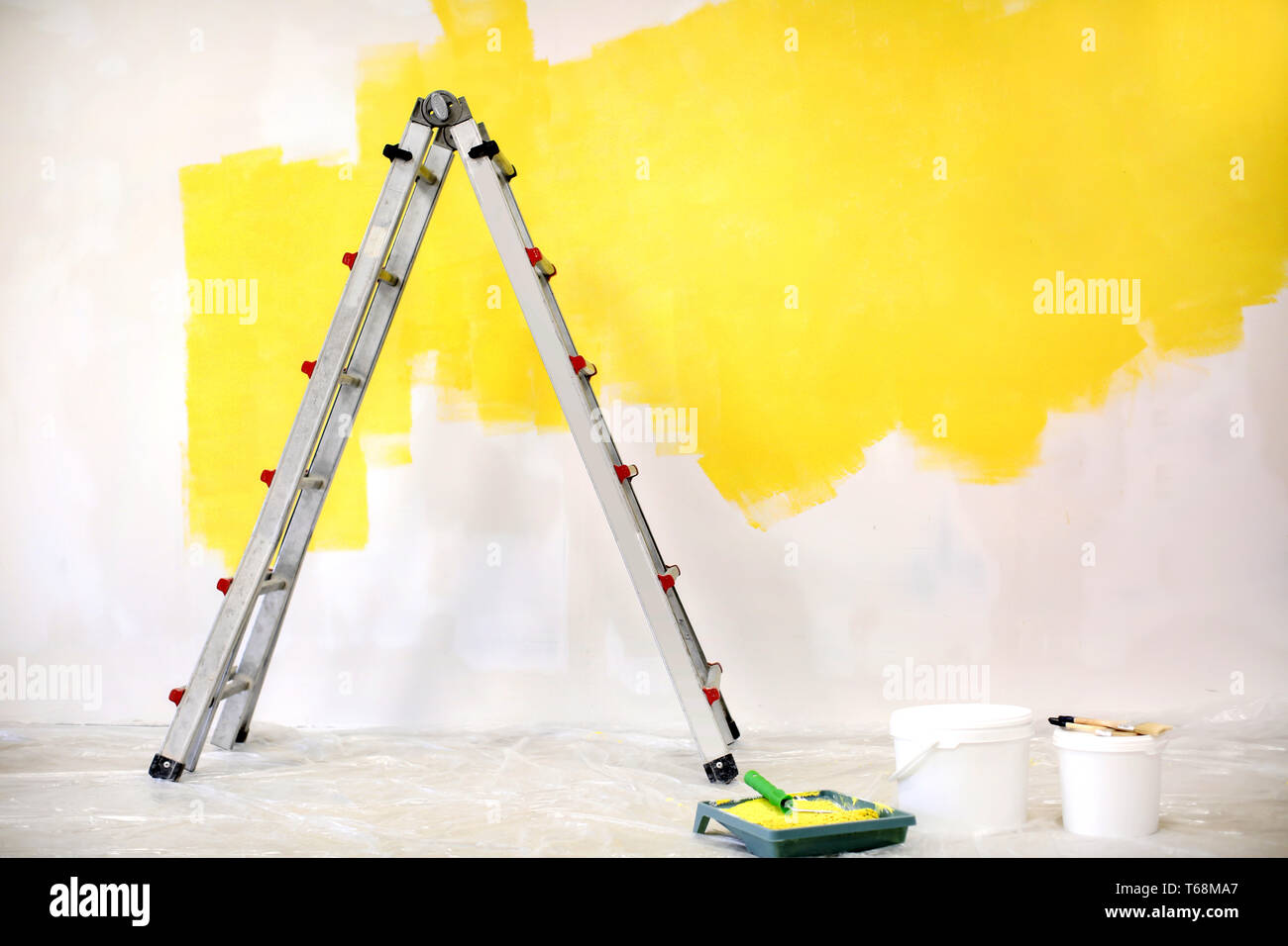 Ladder with paints in buckets and tools near color wall indoors Stock ...