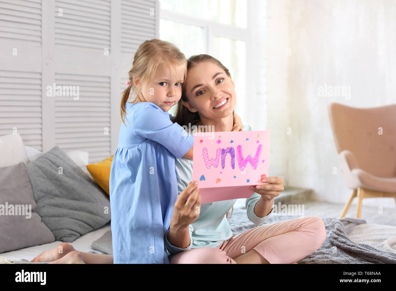 Mother receiving greeting card from her cute little daughter at home ...
