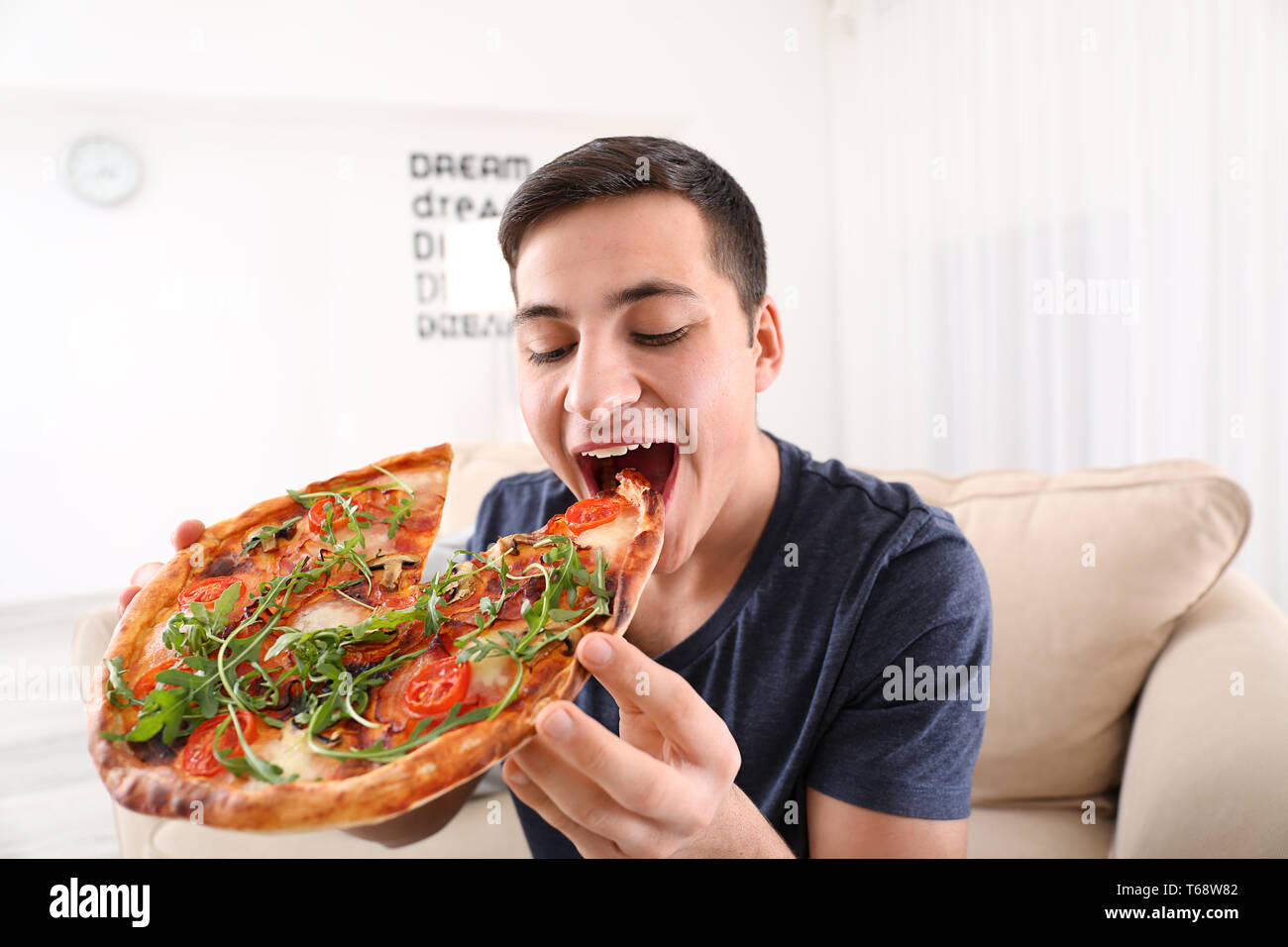 Young man eating pizza sofa hi-res stock photography and images - Alamy
