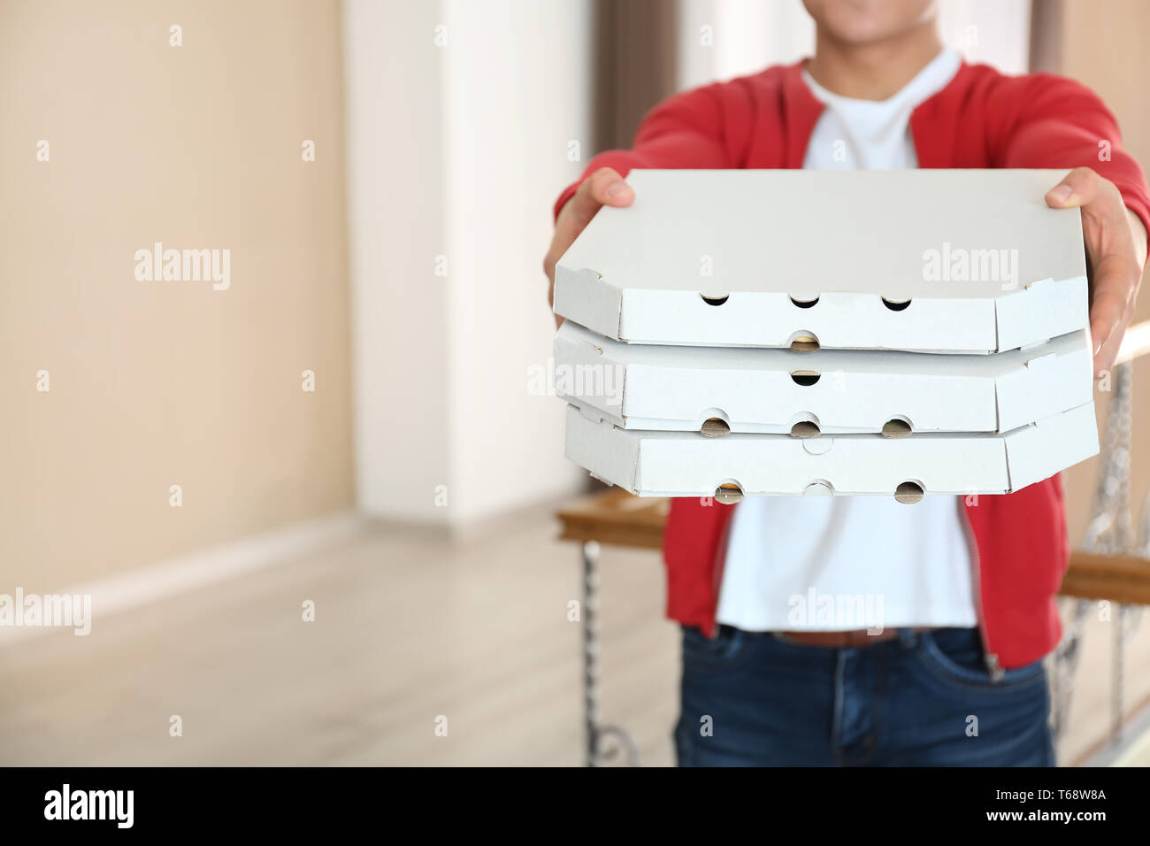 Young man holding pizza boxes indoors Stock Photo - Alamy