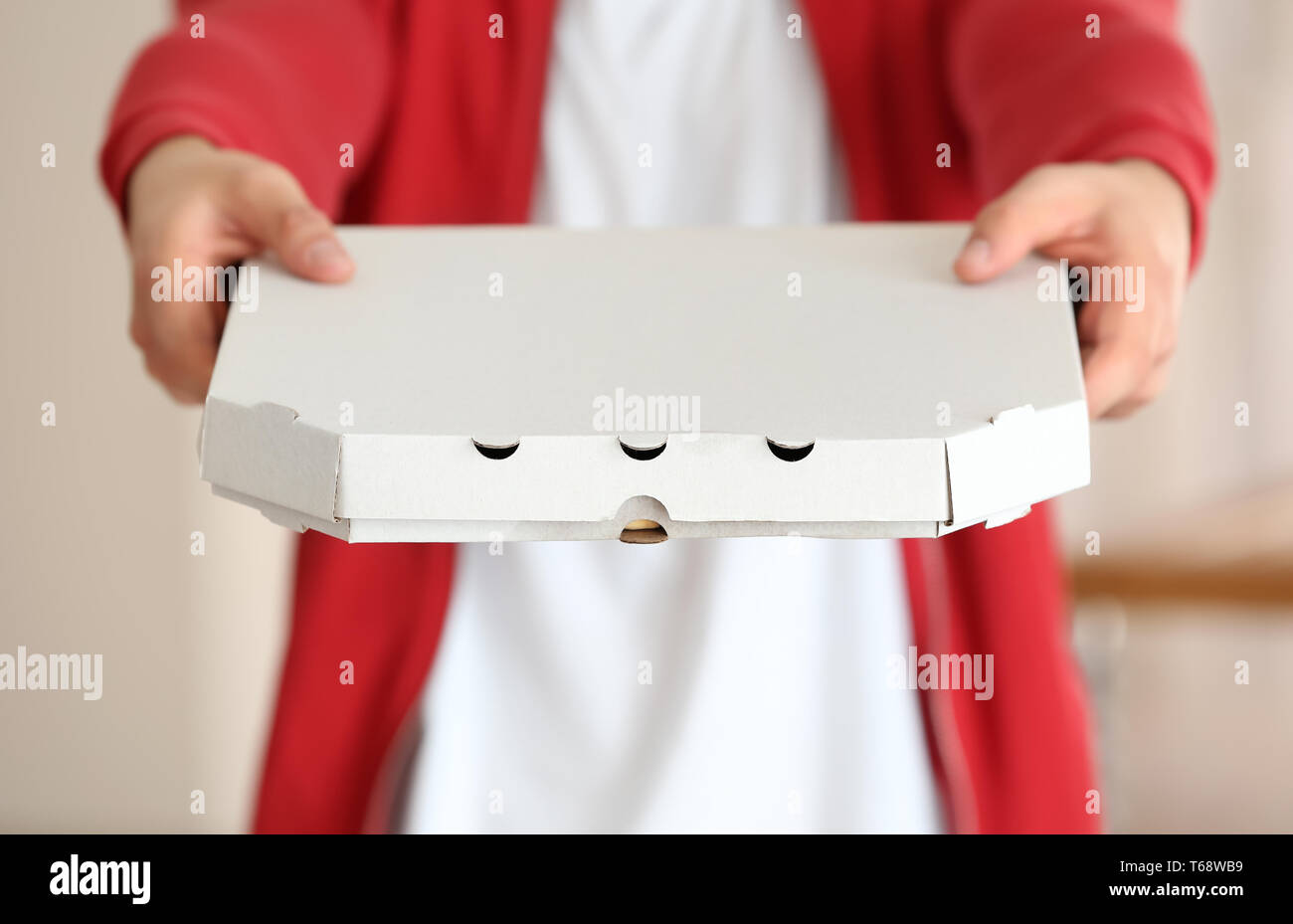Young man holding pizza box indoors Stock Photo - Alamy
