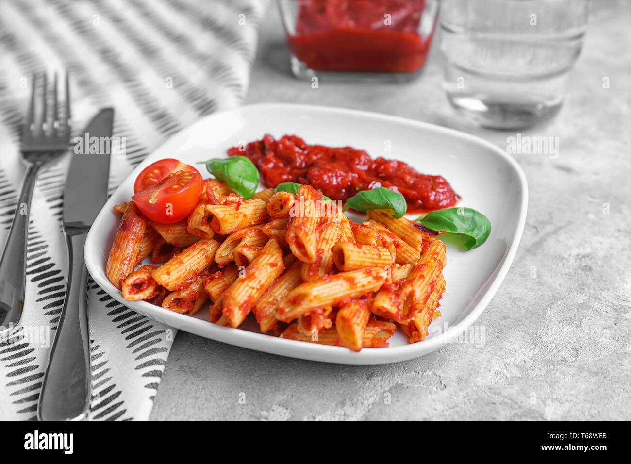 Plate with delicious penne pasta and garnish on table Stock Photo - Alamy
