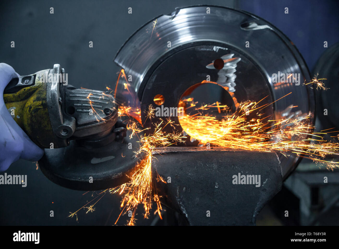 A close-up of a car mechanic using a metal grinder to cut bearing in an ...