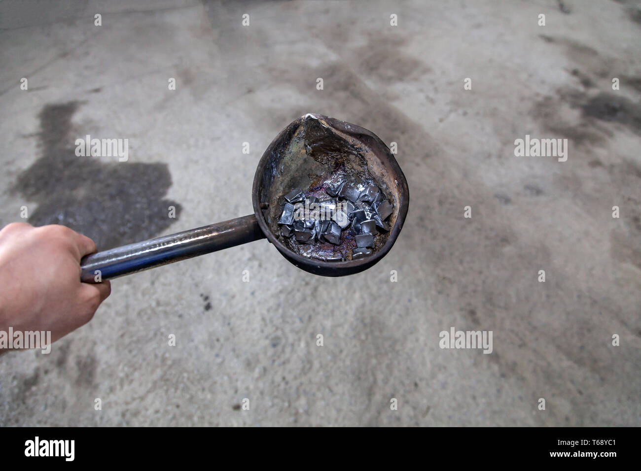 Close-up of a blacksmith man holding in his hand a metal pan with a ...