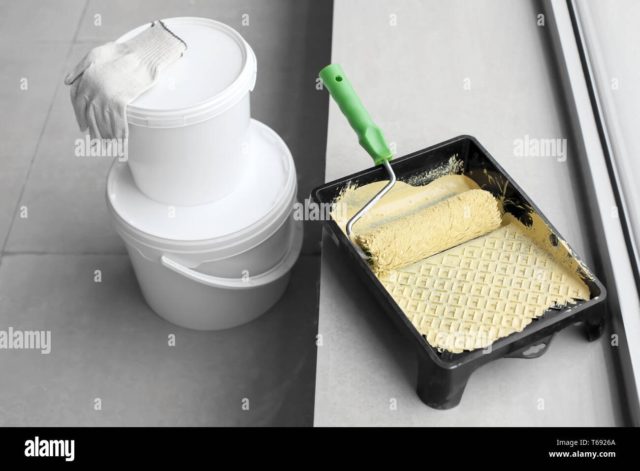 Paint tray with roller and buckets near window indoors Stock Photo - Alamy