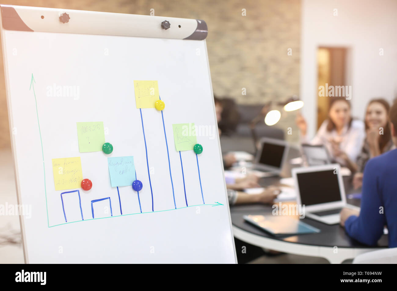 Flip chart and office employees on background. Business meeting Stock ...