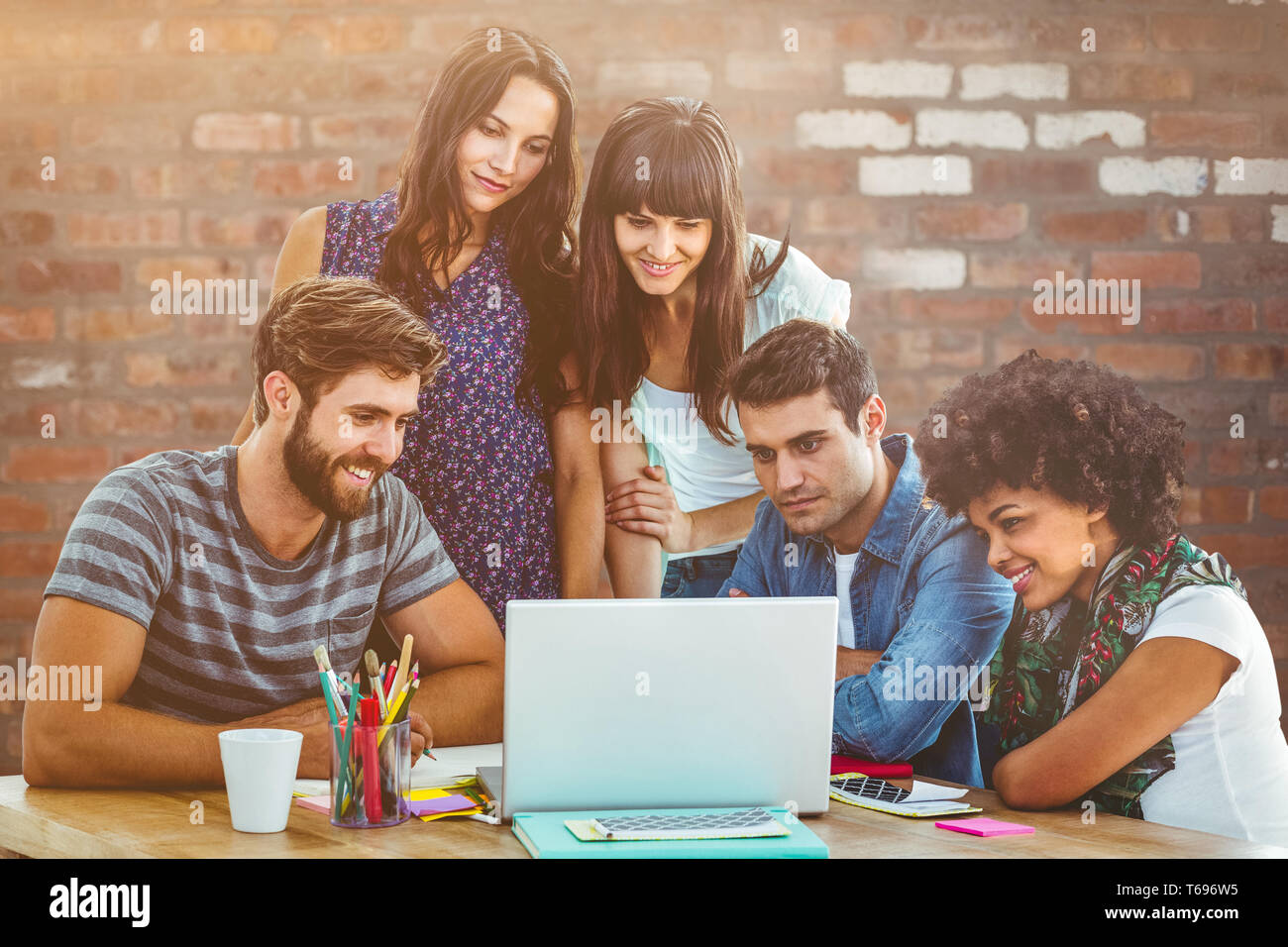 Composite image of happy creative business team gathered around a ...