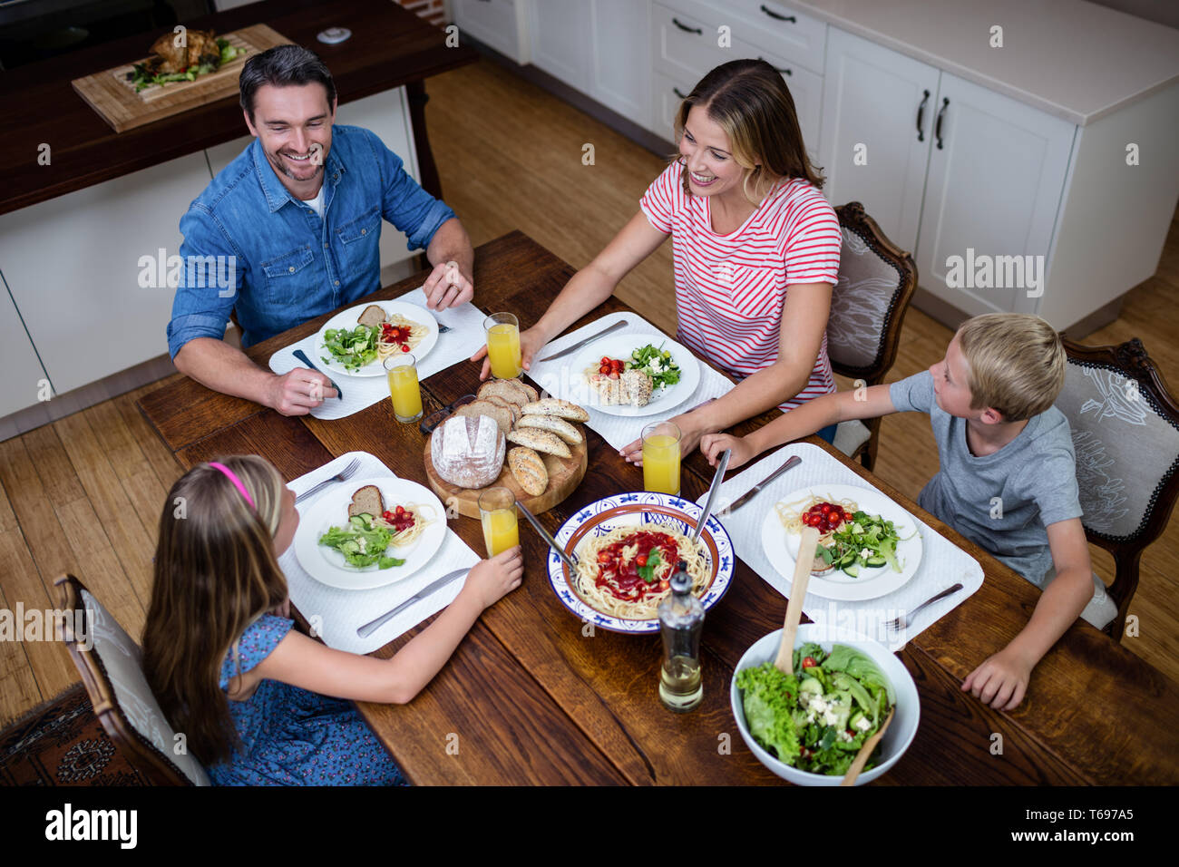 Happy family talking to each other while having meal in kitchen Stock ...