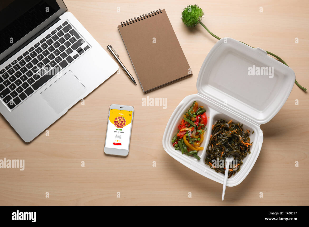 Cell phone with open page of food delivery site on screen, laptop and ...