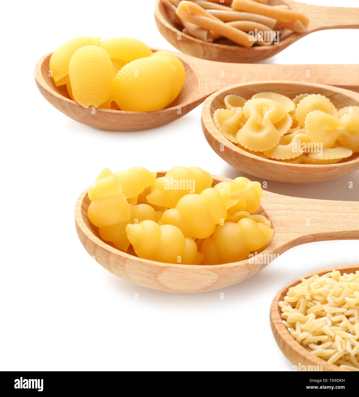 Wooden spoons with different types of pasta on white background Stock ...