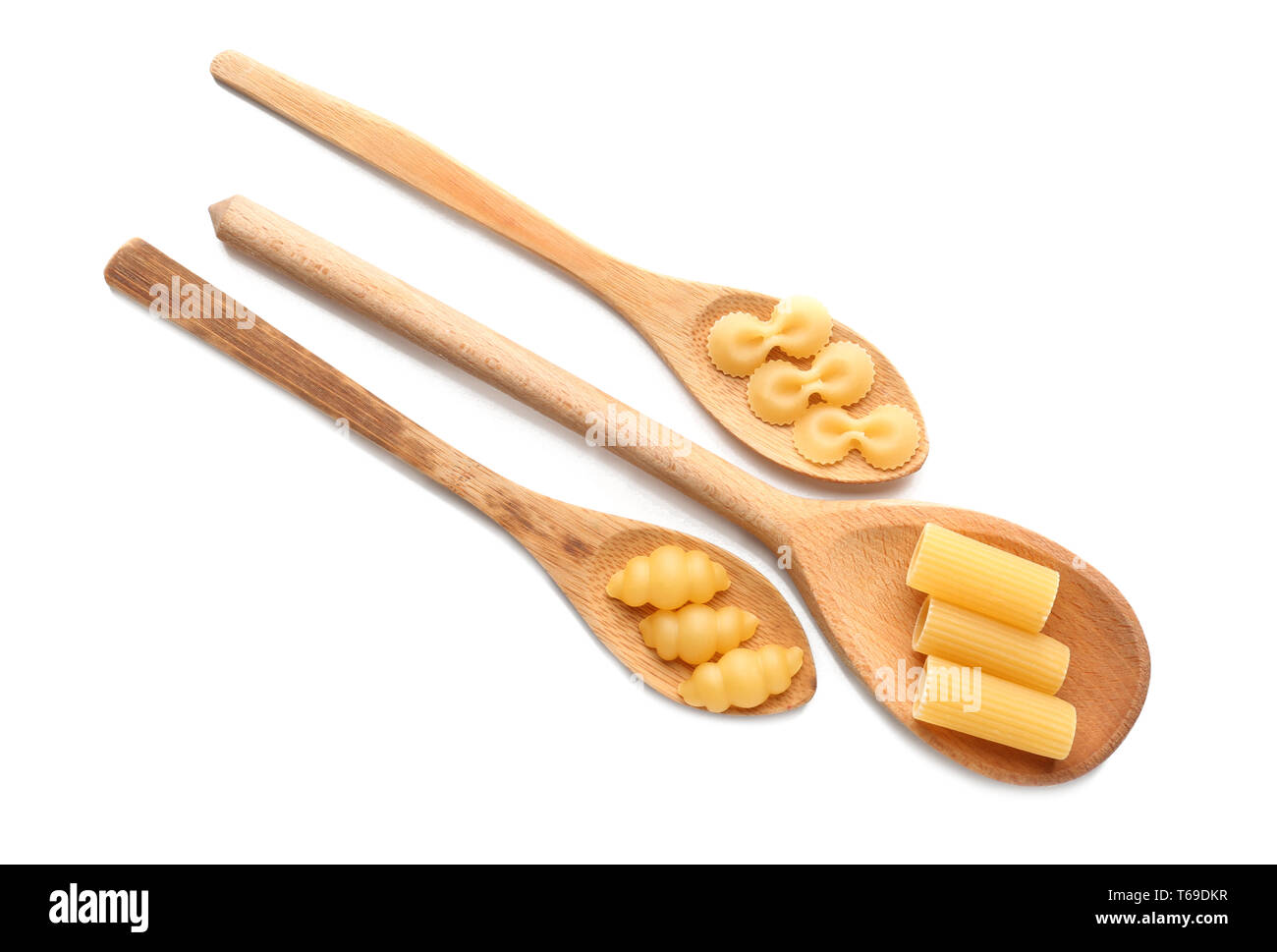 Wooden spoons with different types of pasta on white background Stock ...
