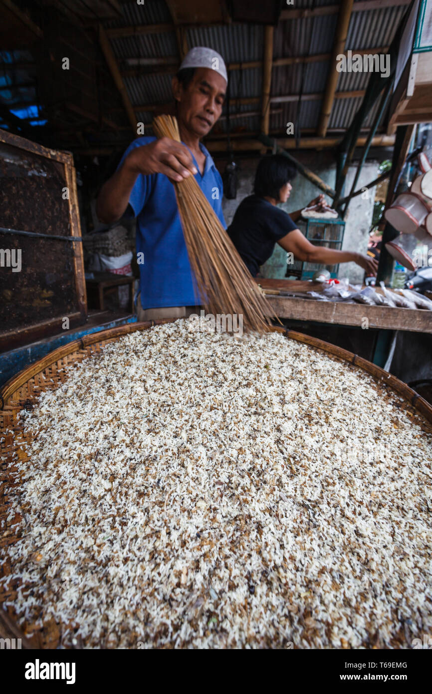 Worker stirring rice getting it ready for sale in outdoor street market ...