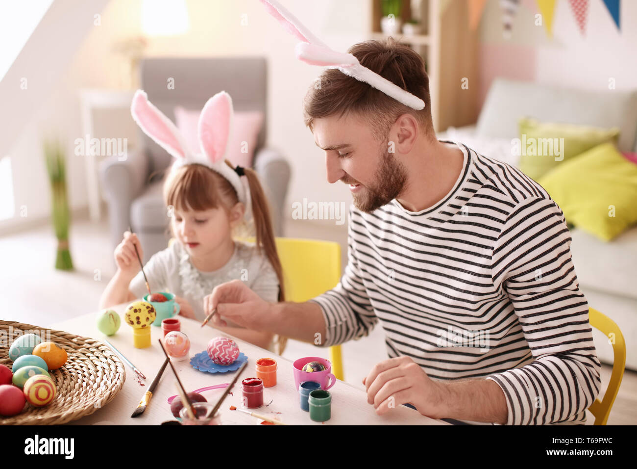 Father painting Easter eggs with his daughter at table Stock Photo - Alamy