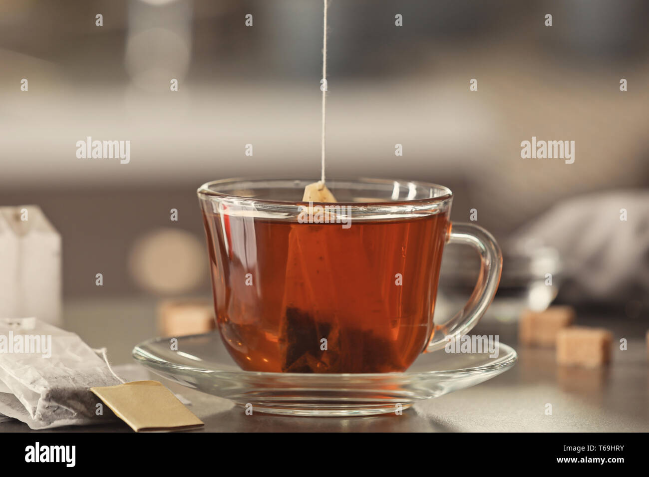 Dipping tea bag into cup on table Stock Photo - Alamy