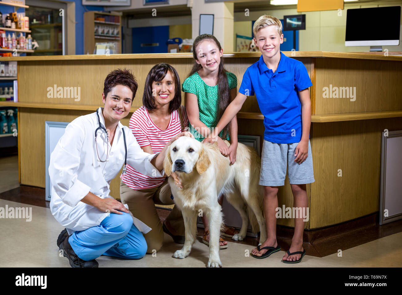 Woman vet and happy family smiling and posing with a dog Stock Photo ...