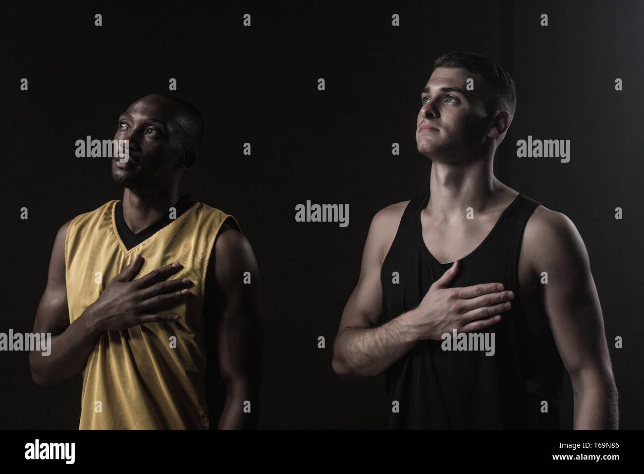 Portrait of basketball players looking up and putting hand on heart ...