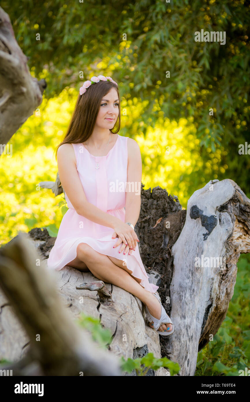 Beautiful girl sitting on a fallen tree in the forest Stock Photo - Alamy