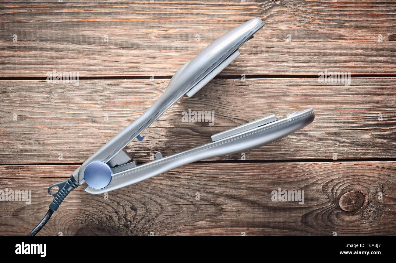 Iron for leveling hair on a wooden table. Hair straighteners. Top view ...