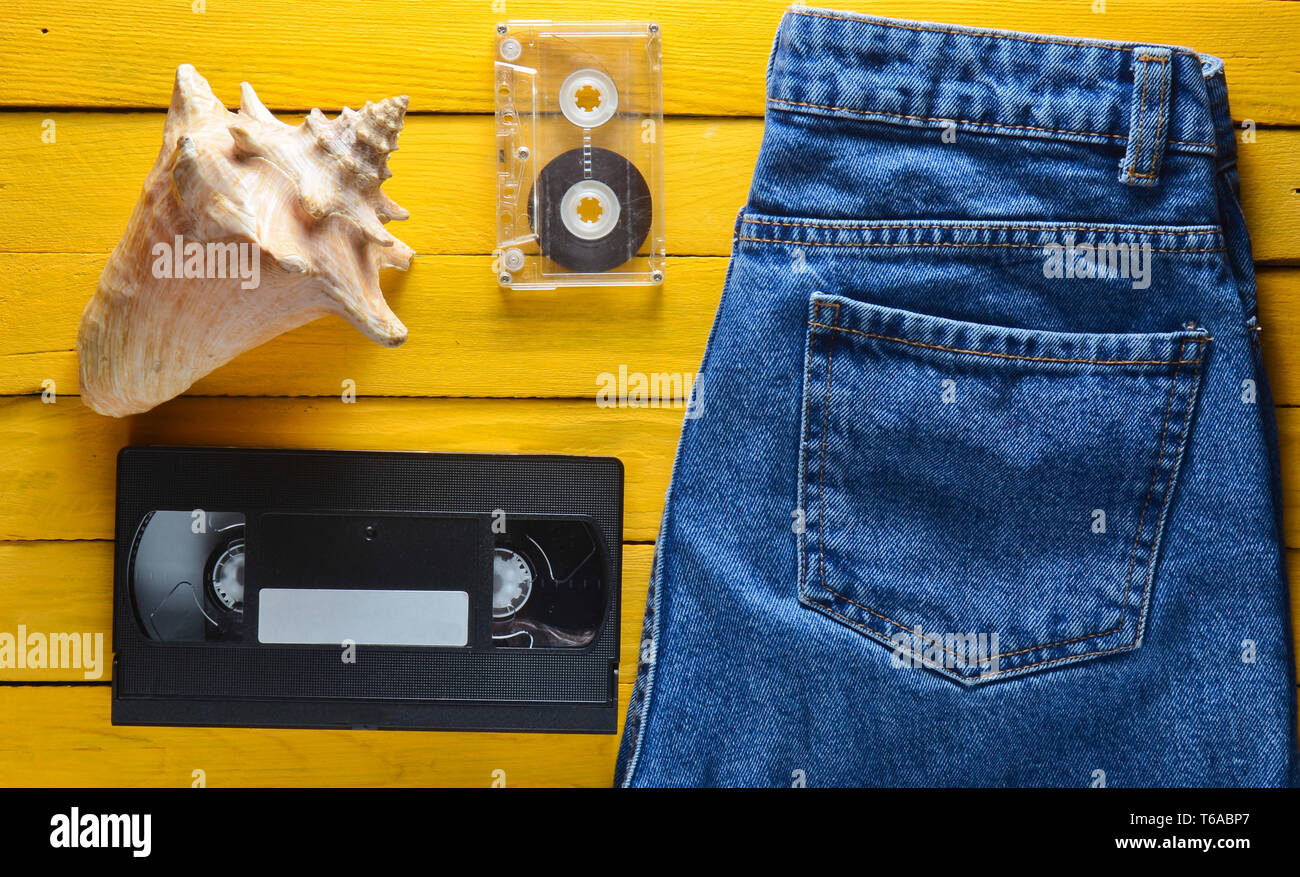 Accessories x generation: jeans, audio cassette, vhs, shell on a wooden ...