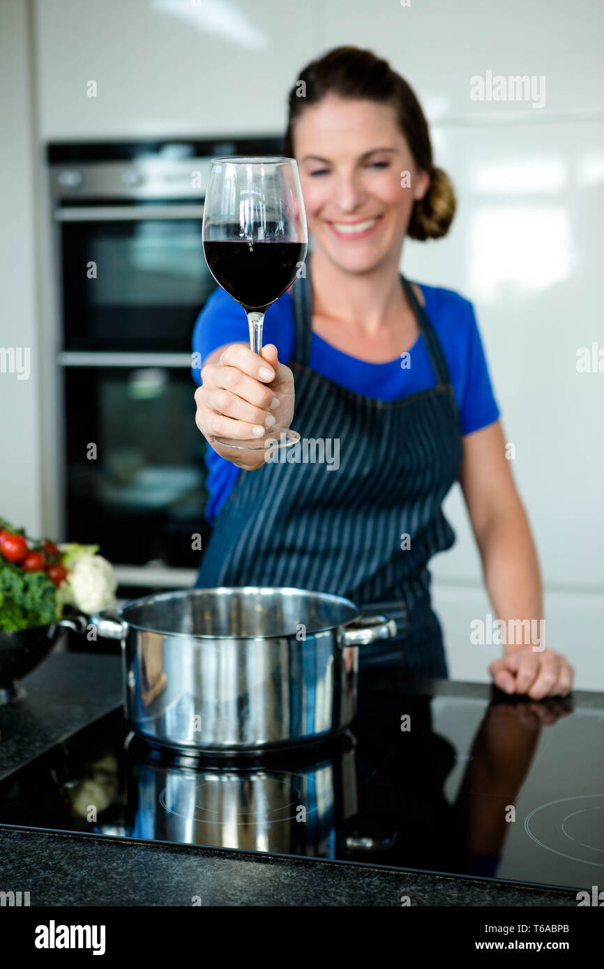 smiling woman cooking on the stove top and drinking red wine Stock ...