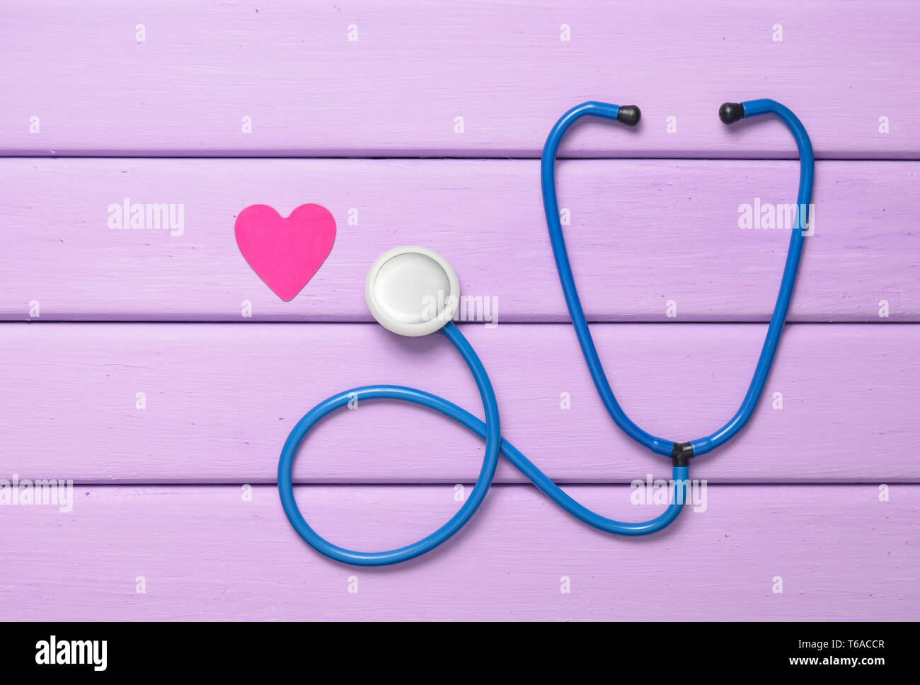 Stethoscope and heart on a purple wooden table. Cardiology equipment ...