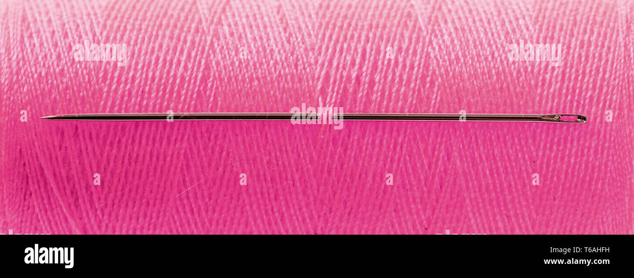 Pink threat with needle, full frame, focus on needle Stock Photo - Alamy