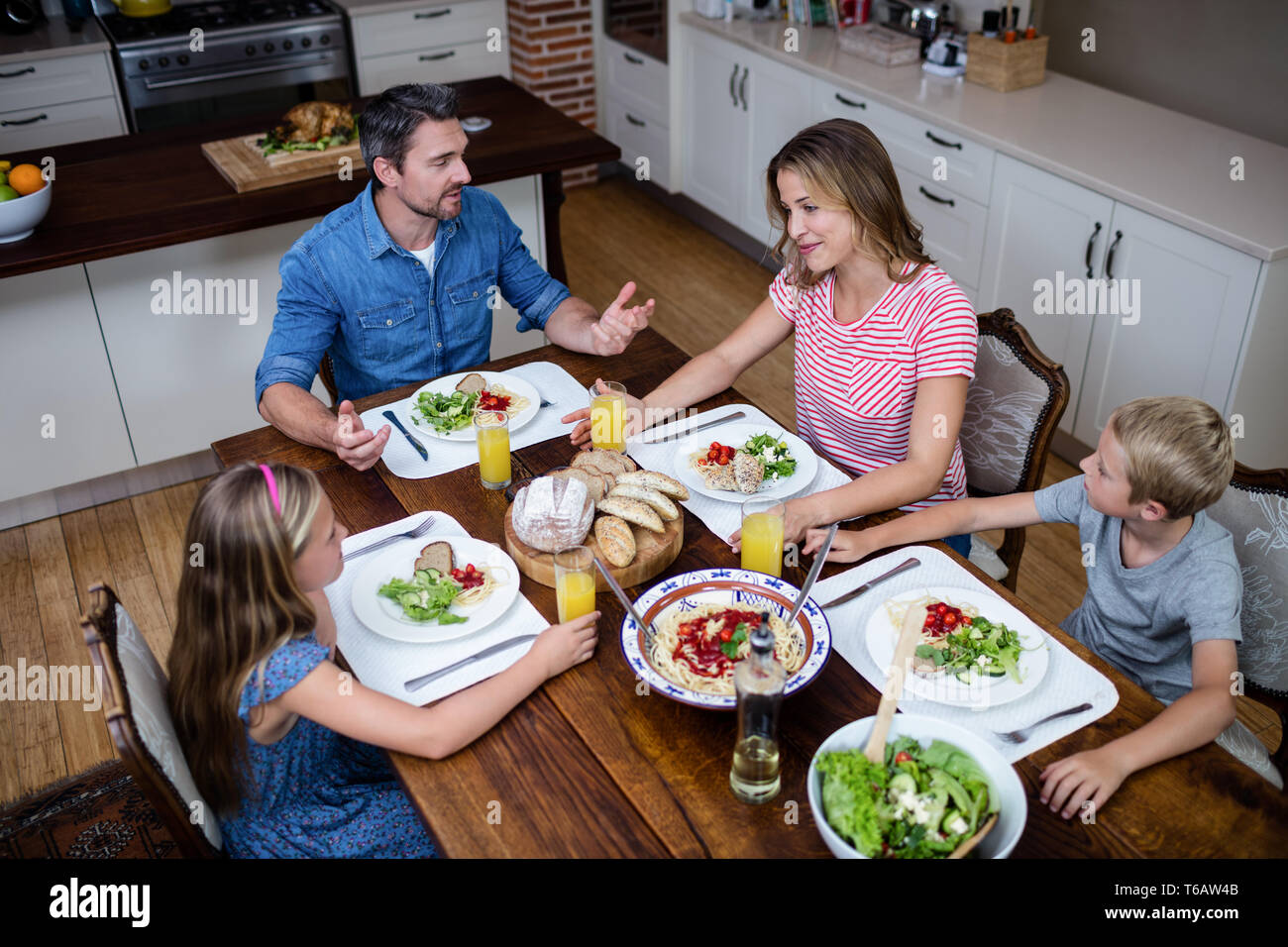 Happy family talking to each other while having meal in kitchen Stock ...