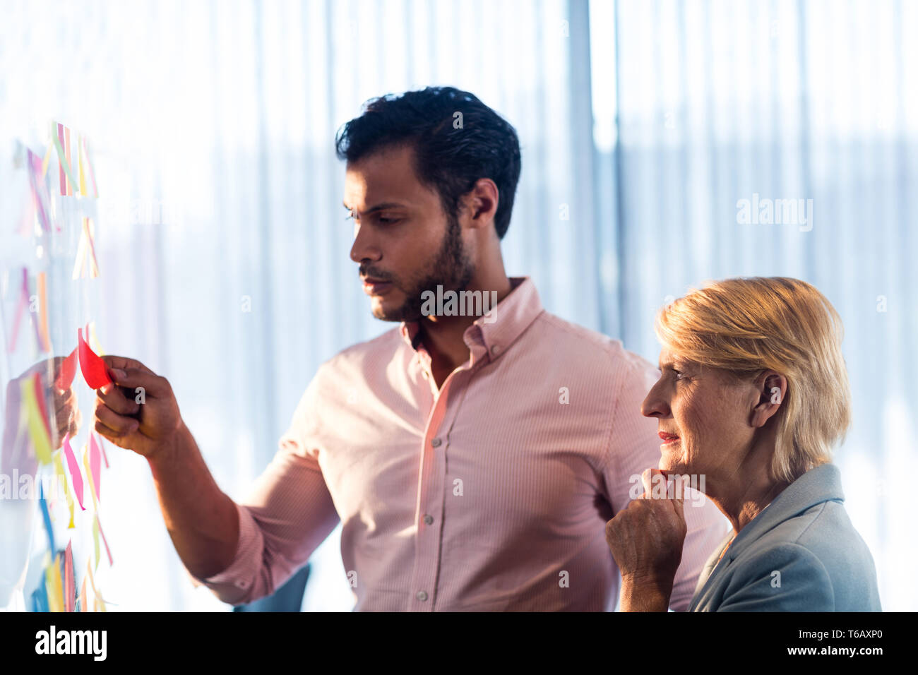 Side view of two business people looking at post it wall Stock Photo ...