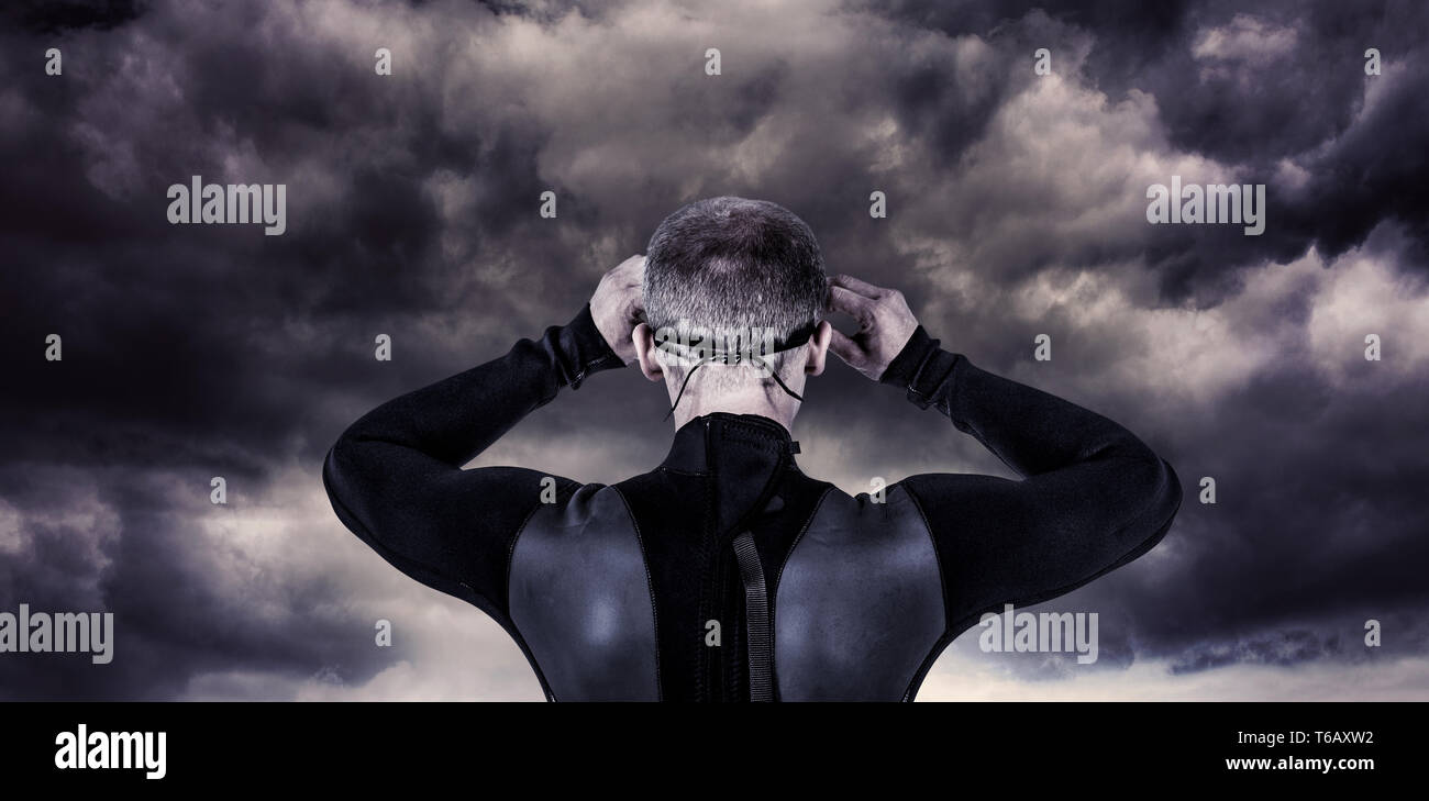 Composite image of rear view of swimmer in wetsuit wearing swimming ...