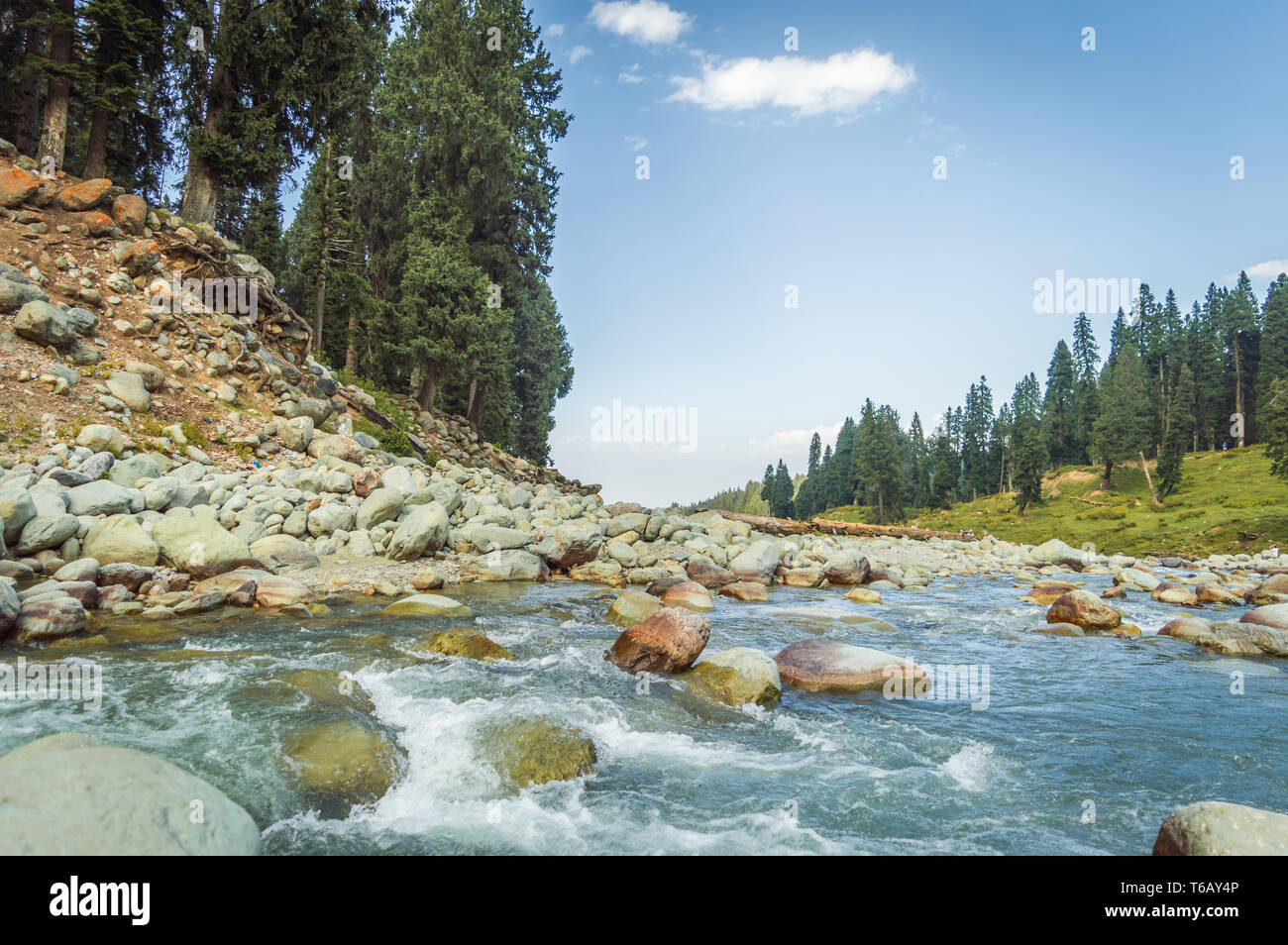 A crystal clear stream with blue waters flowing through a wide mountain ...